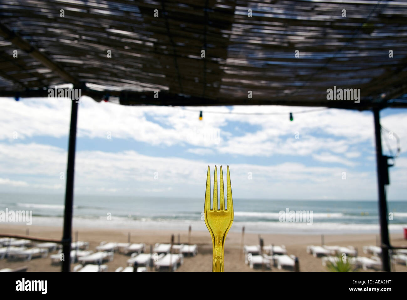 a detail of a yellow fork close up at a beach bar with the beach and ...