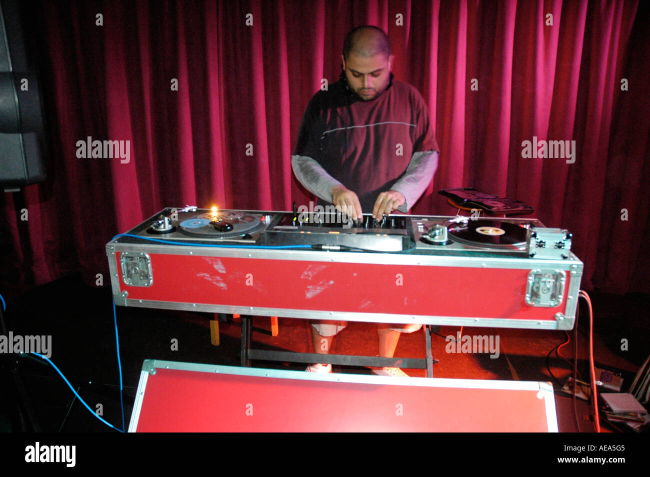 Portrait of a DJ at work with his records and mixer table in a ...