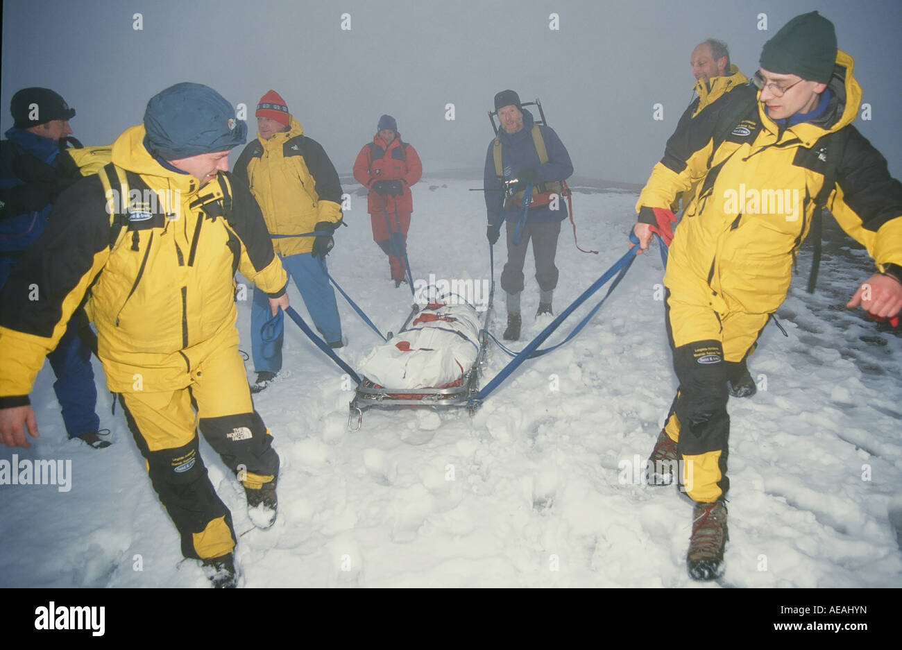 Mountain rescue team members drag a stretcher with the body of a heart ...