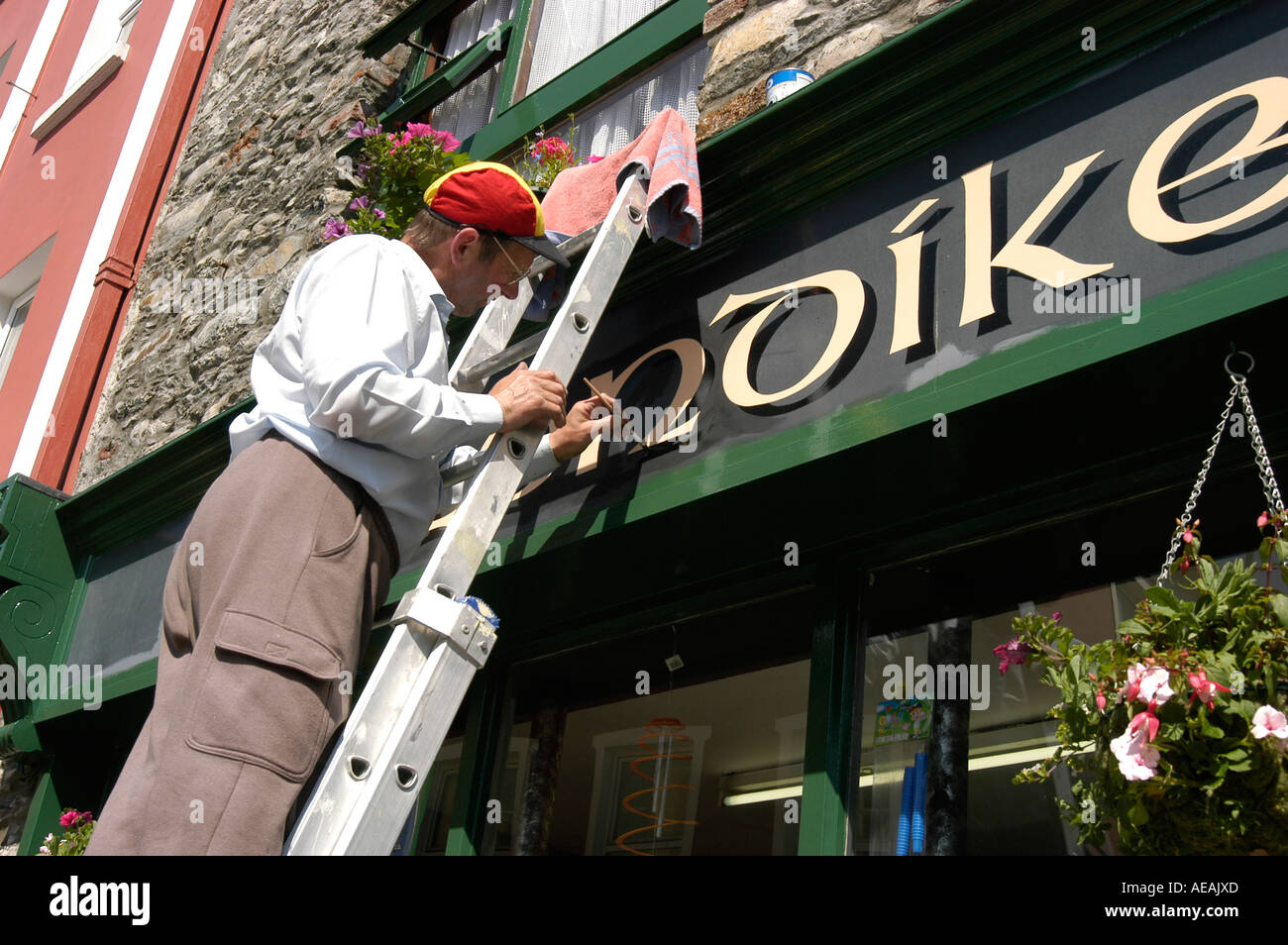 man painting shop front sign Killarney Ireland with traditional celtic ...