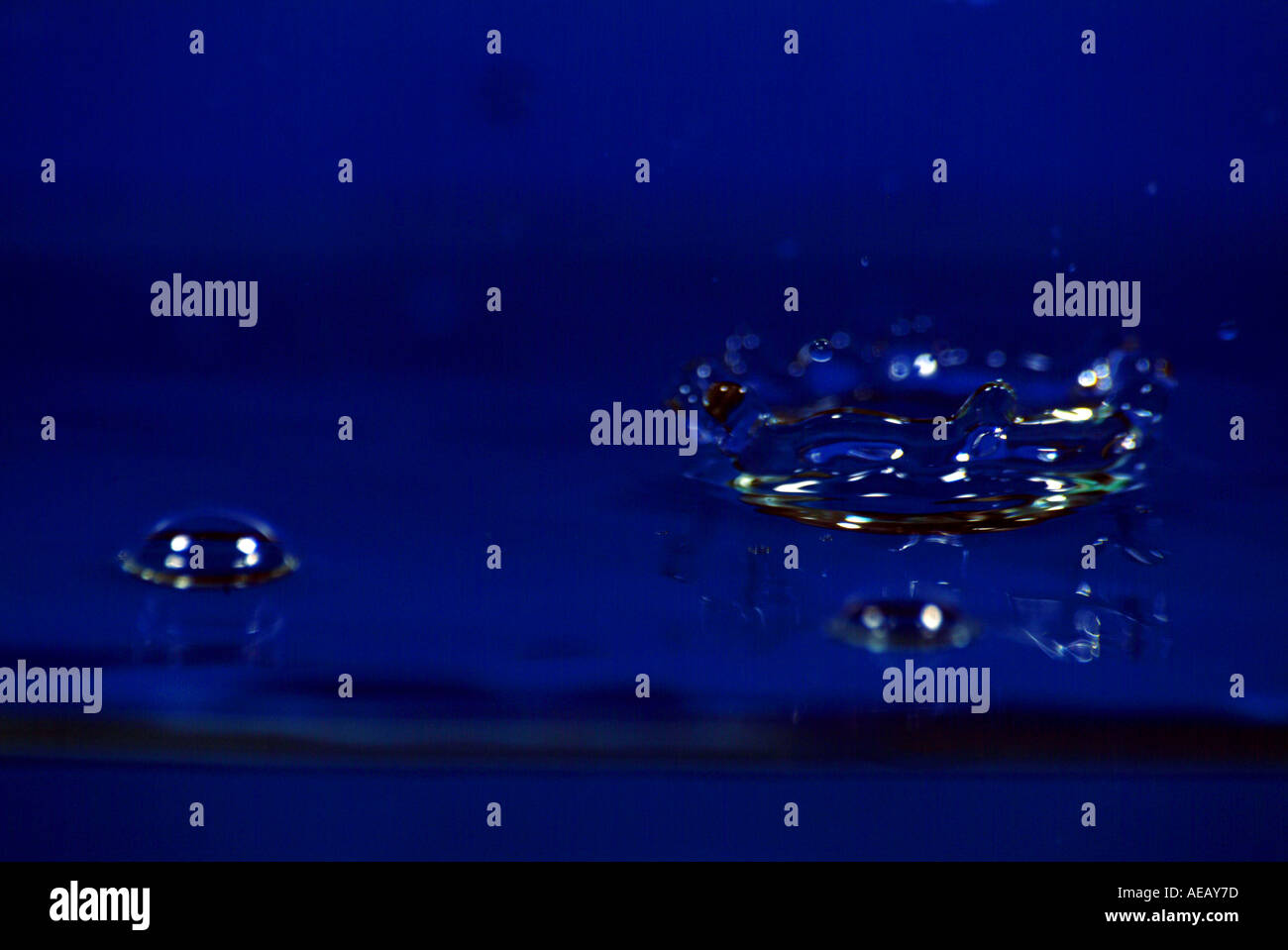 water droplet hitting surface of water and creating a reactive shape ...