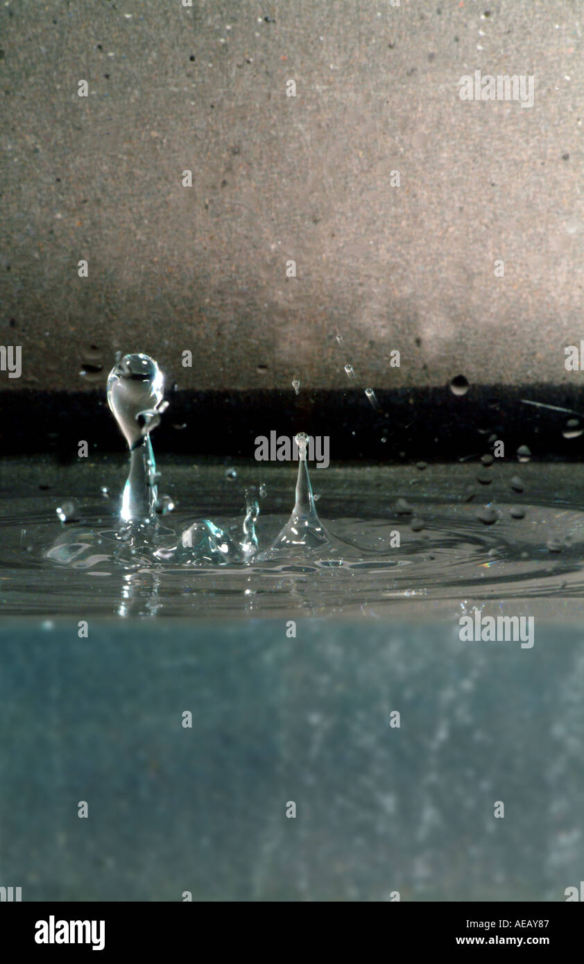 water droplet hitting surface of water and creating a reactive shape ...