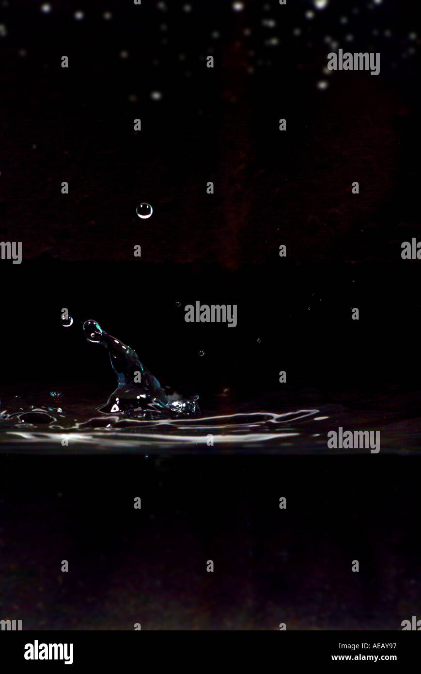 water droplet hitting surface of water and creating a reactive shape ...