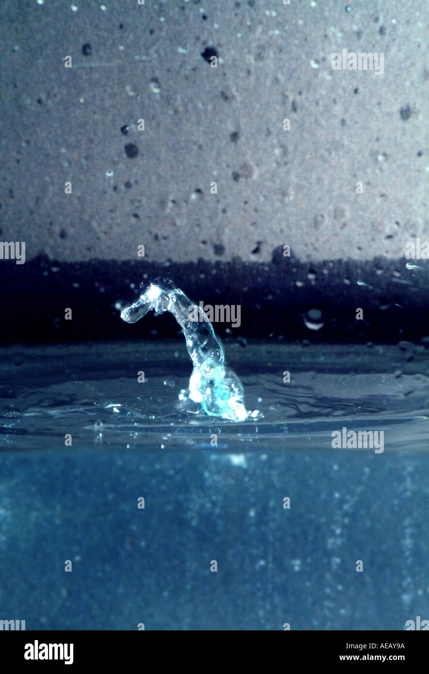 water droplet hitting surface of water and creating a reactive shape ...