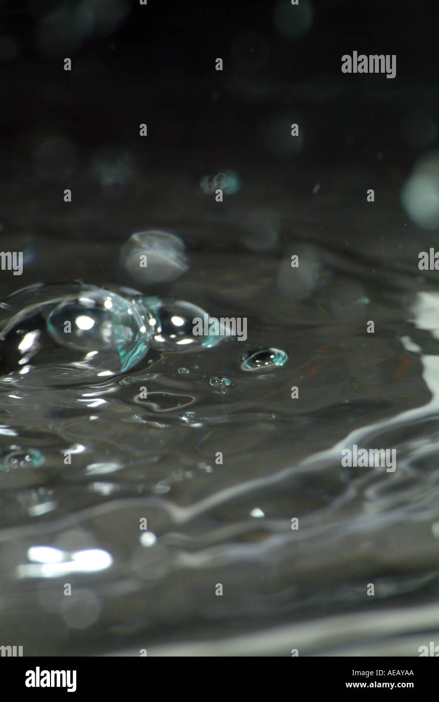 water droplet hitting surface of water and creating a reactive shape ...