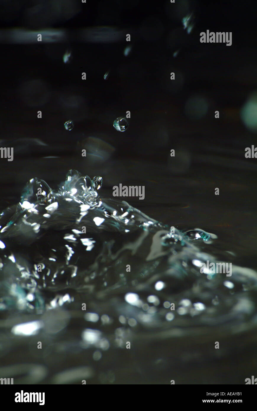 water droplet hitting surface of water and creating a reactive shape ...