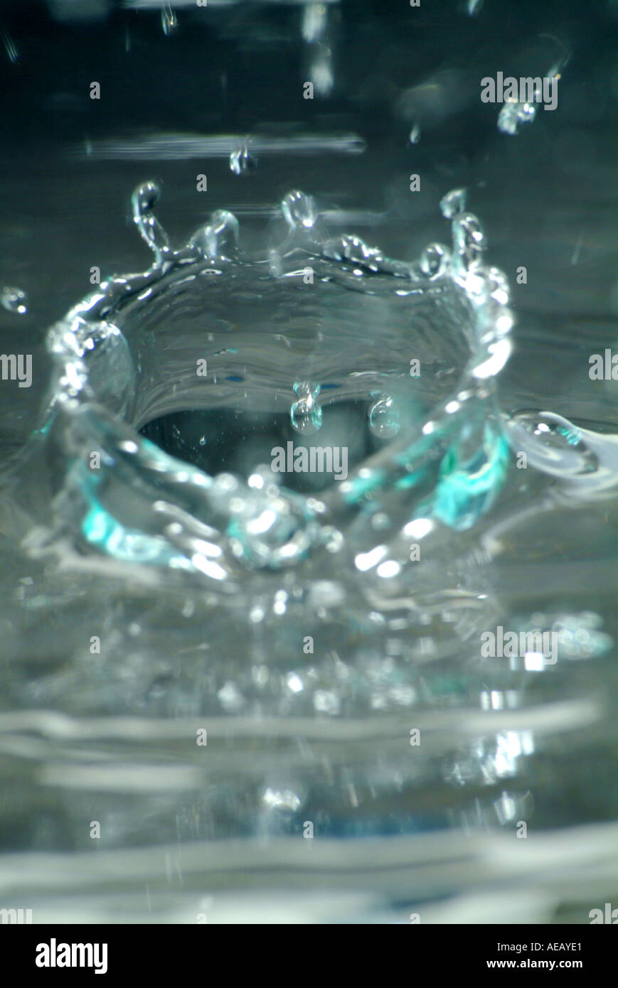 water droplet hitting surface of water and creating a reactive shape ...