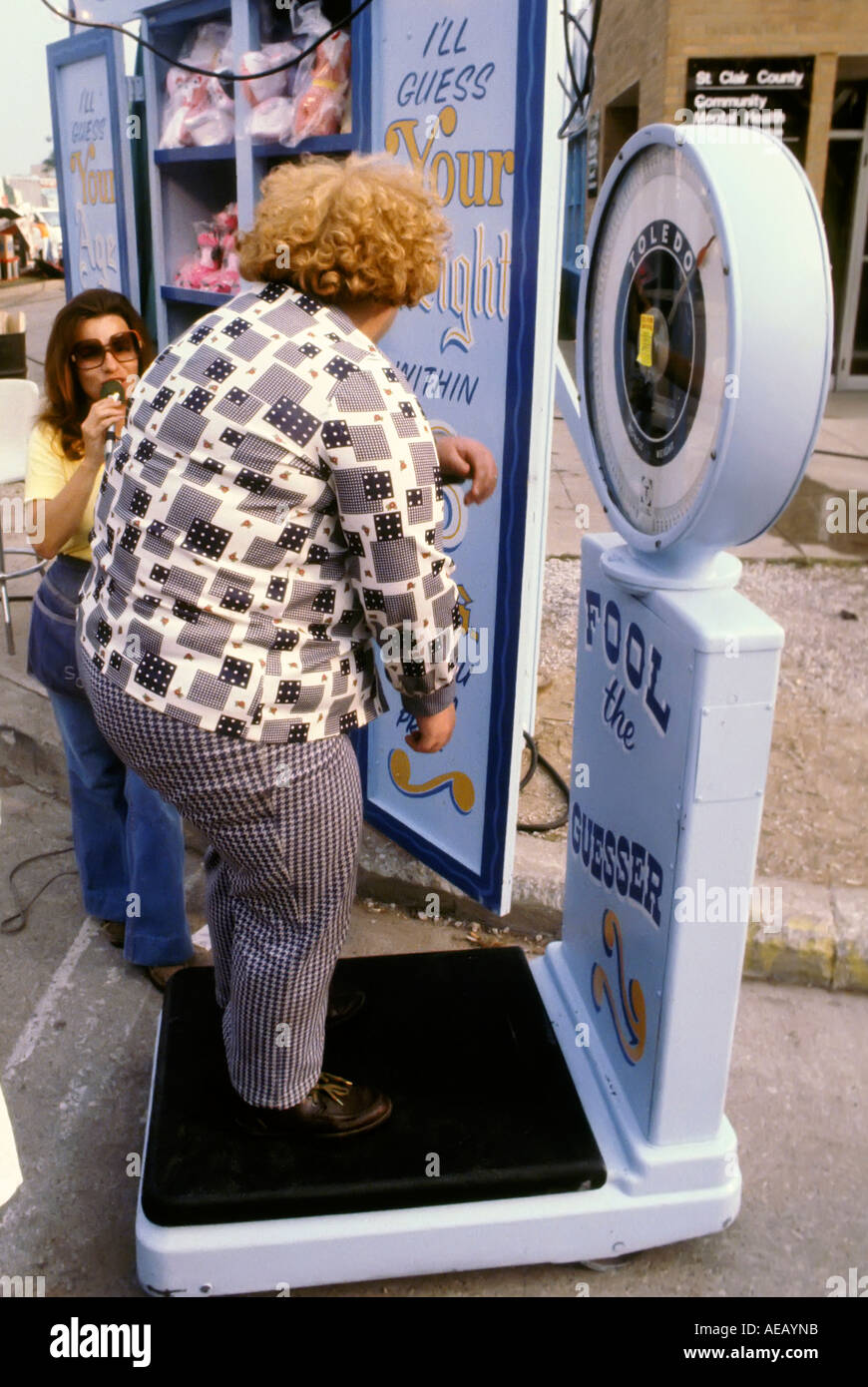 Adult female on a scale as carnival weight guesser estimates her weight ...