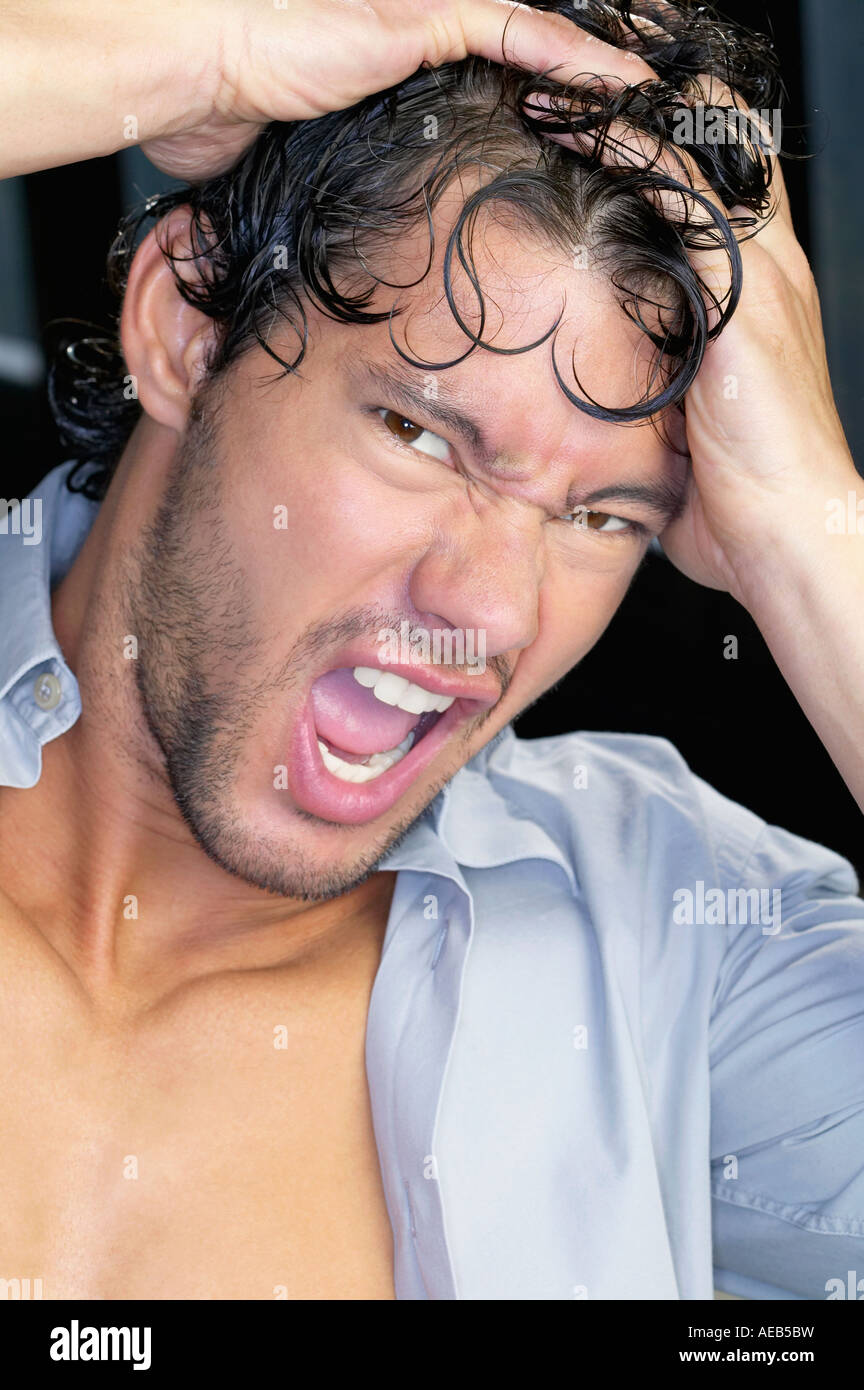 Close up of young man yelling with hands on head Stock Photo - Alamy