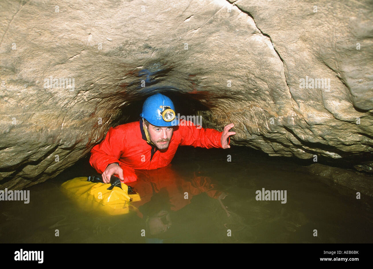 A caver going through a duck in Valley Entrance, Kingsdale, Yorkshire ...