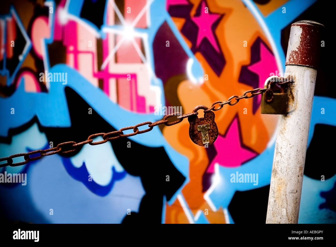 Dark image of a rusty padlock and chain with a graffiti background ...