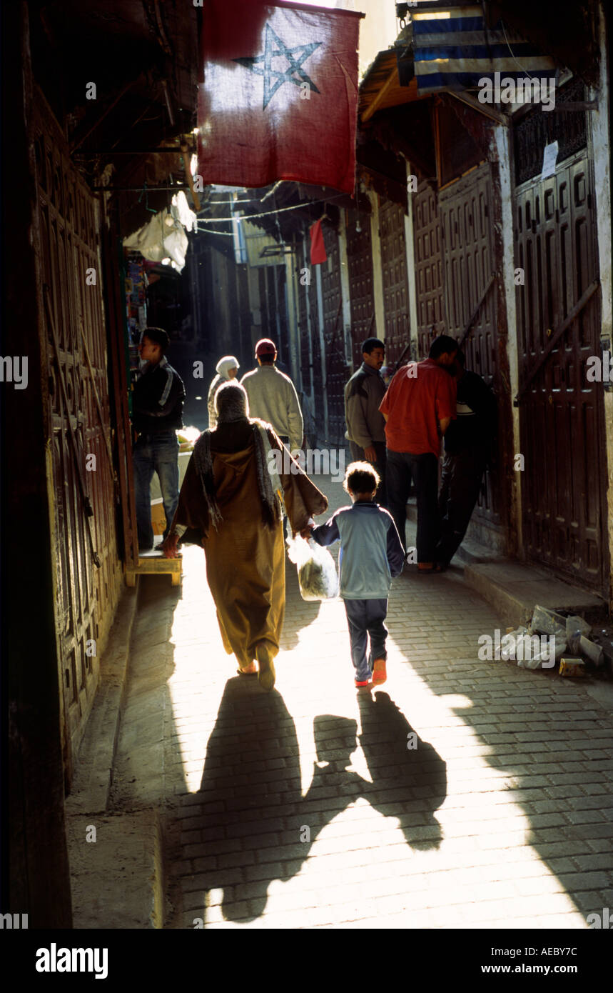 A mother and child holding hands walk under the red flag of Morocco in ...
