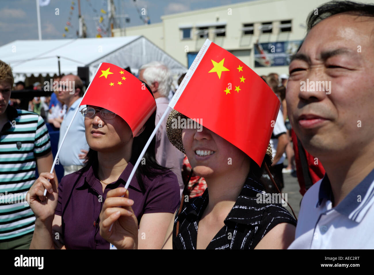 Chinese women and a man use small Chinese flags as sun protection On ...