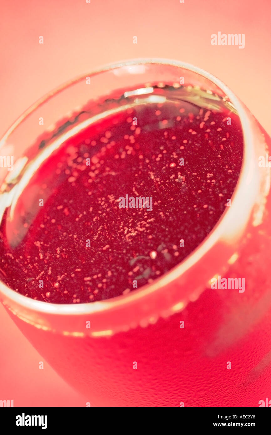 Close up of fizzy red drink in glass against pale background Stock ...