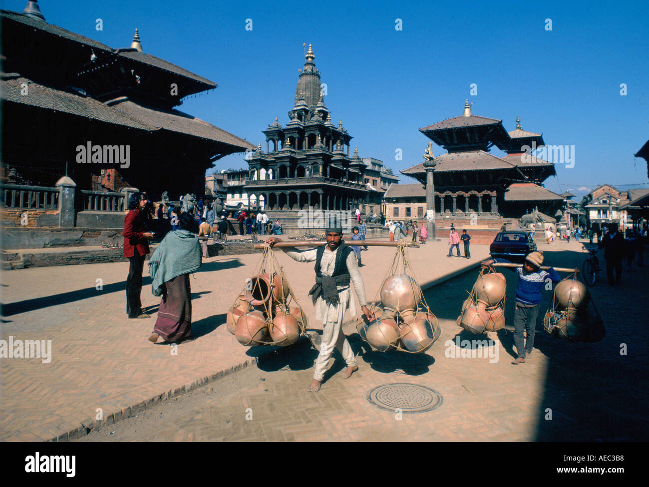 Man and boy carrying heavy pots on shoulder hoists Patan Nepal Stock ...