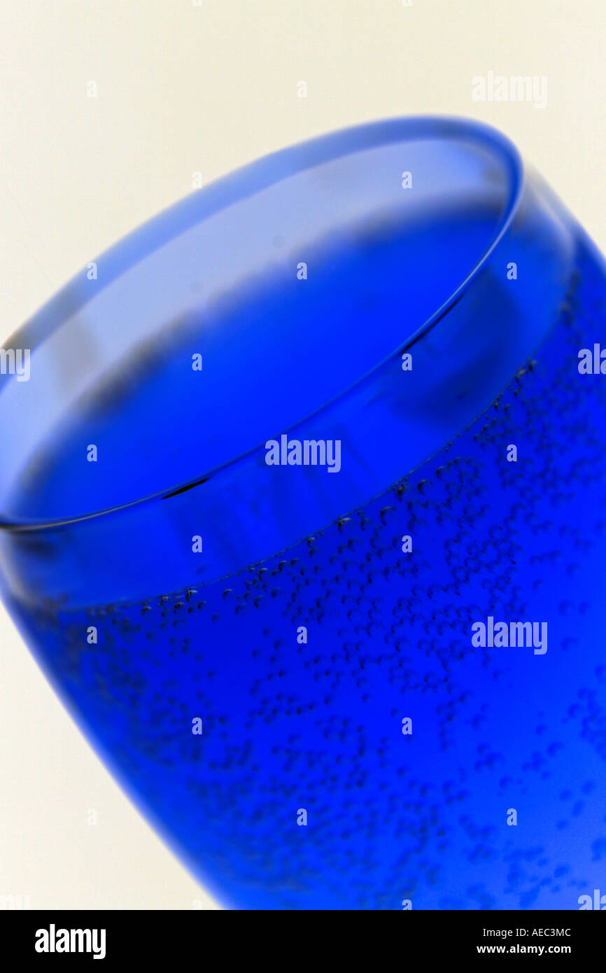 Close up of fizzy blue drink in glass against pale cream background ...