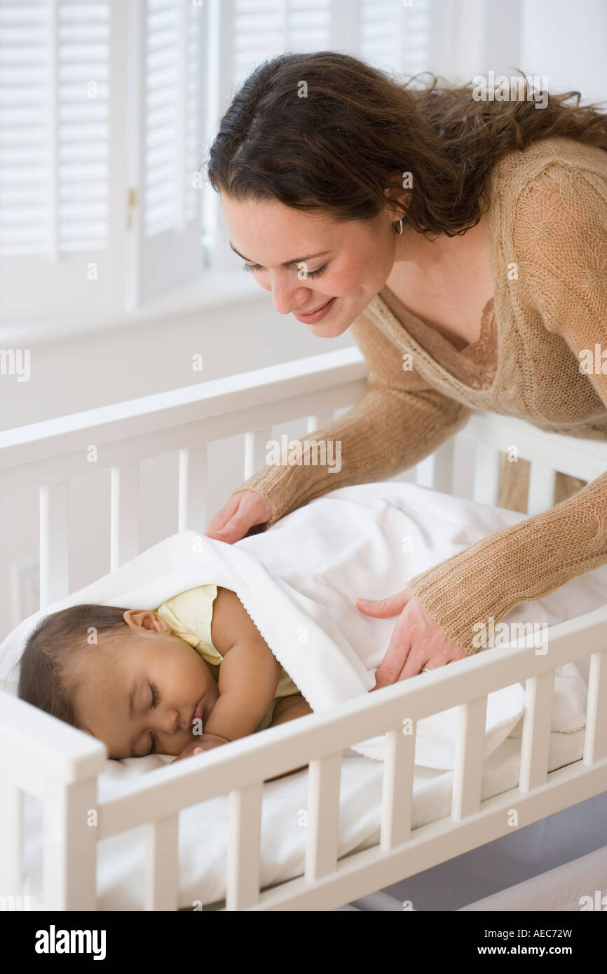 Hispanic mother tucking sleeping baby in crib Stock Photo - Alamy