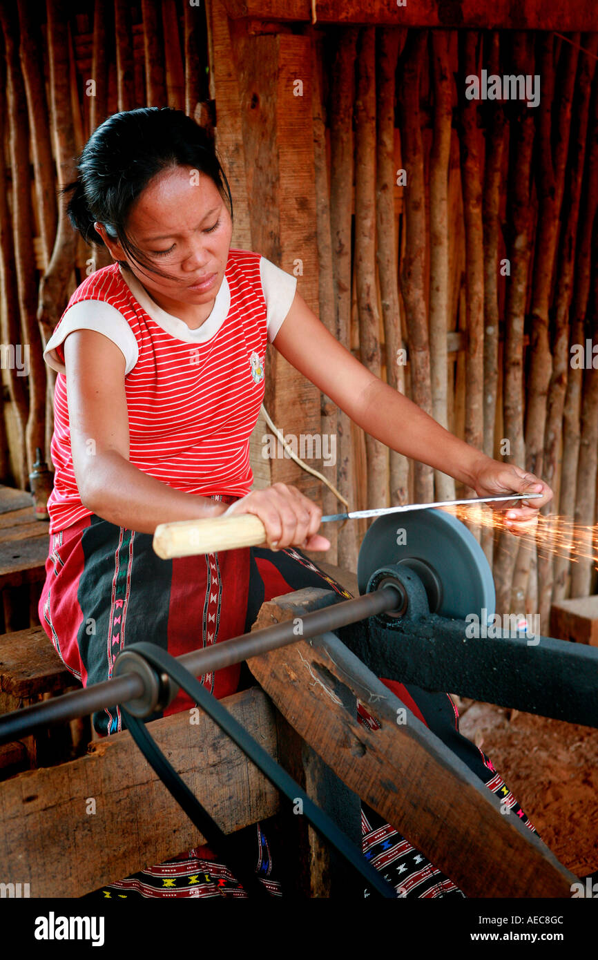 Native woman sharpening a blade at a minority village on the Bolaven ...