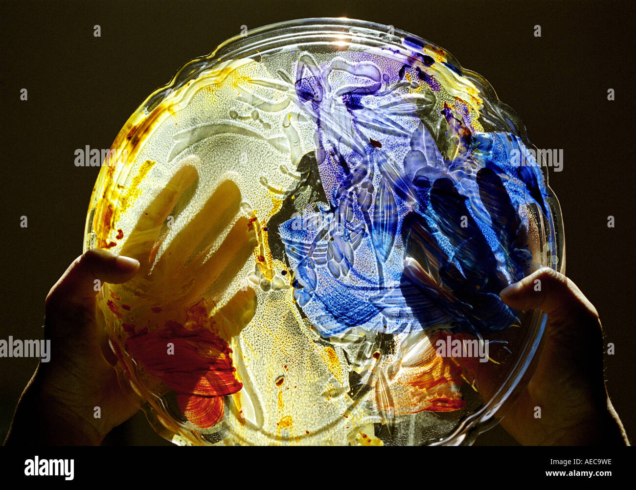 Abstract composition with painted glass held in both hands with back ...