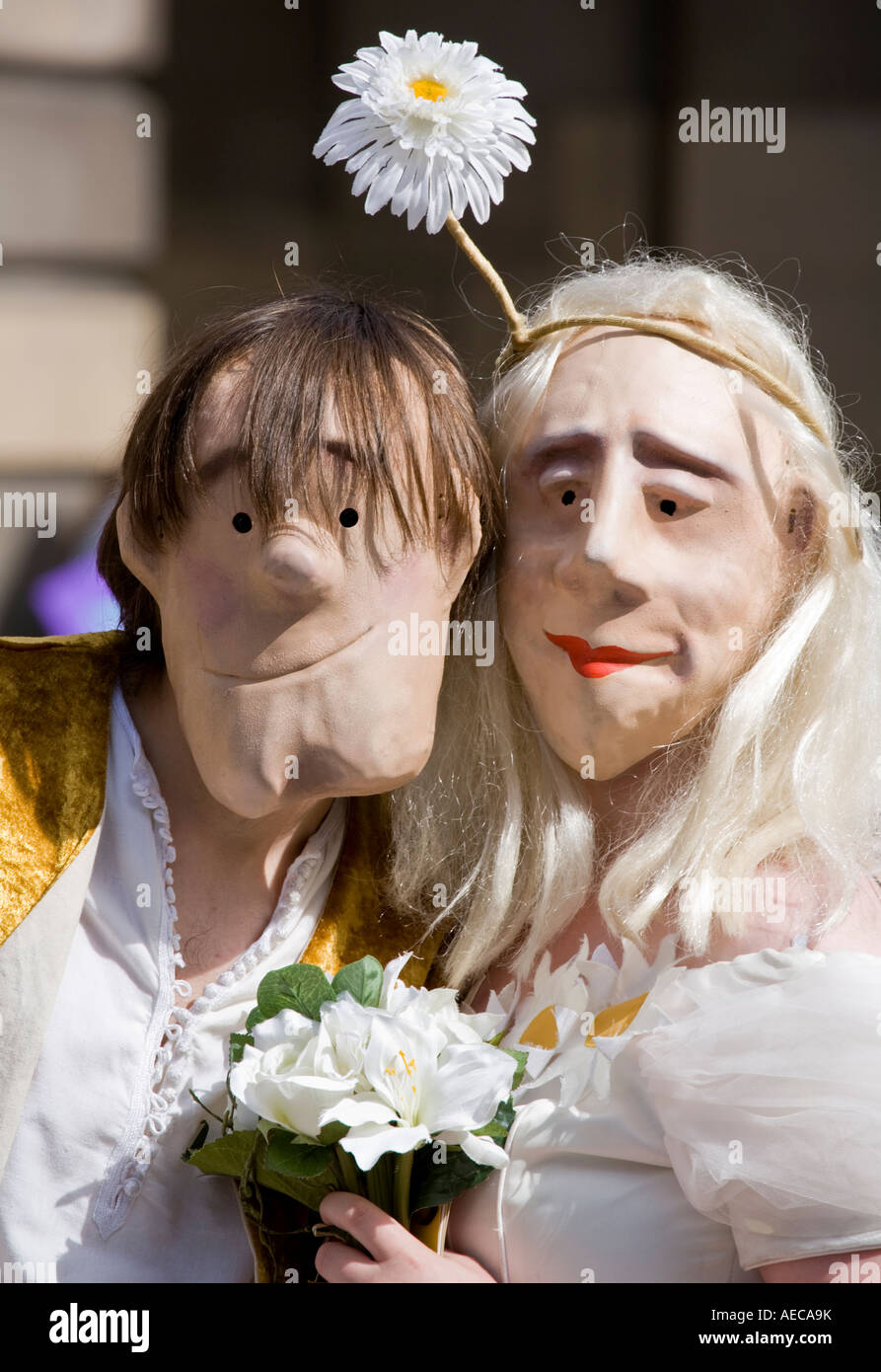 Two actors in papier mache masks pose as a Bride and Groom at the ...