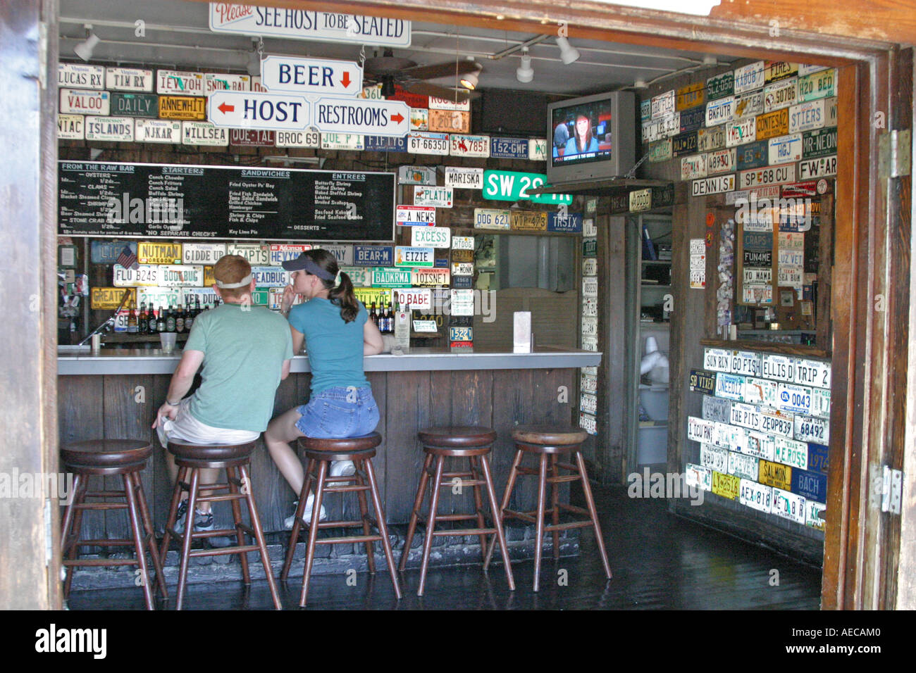 two patrons at a bar with license plate covered walls Stock Photo - Alamy