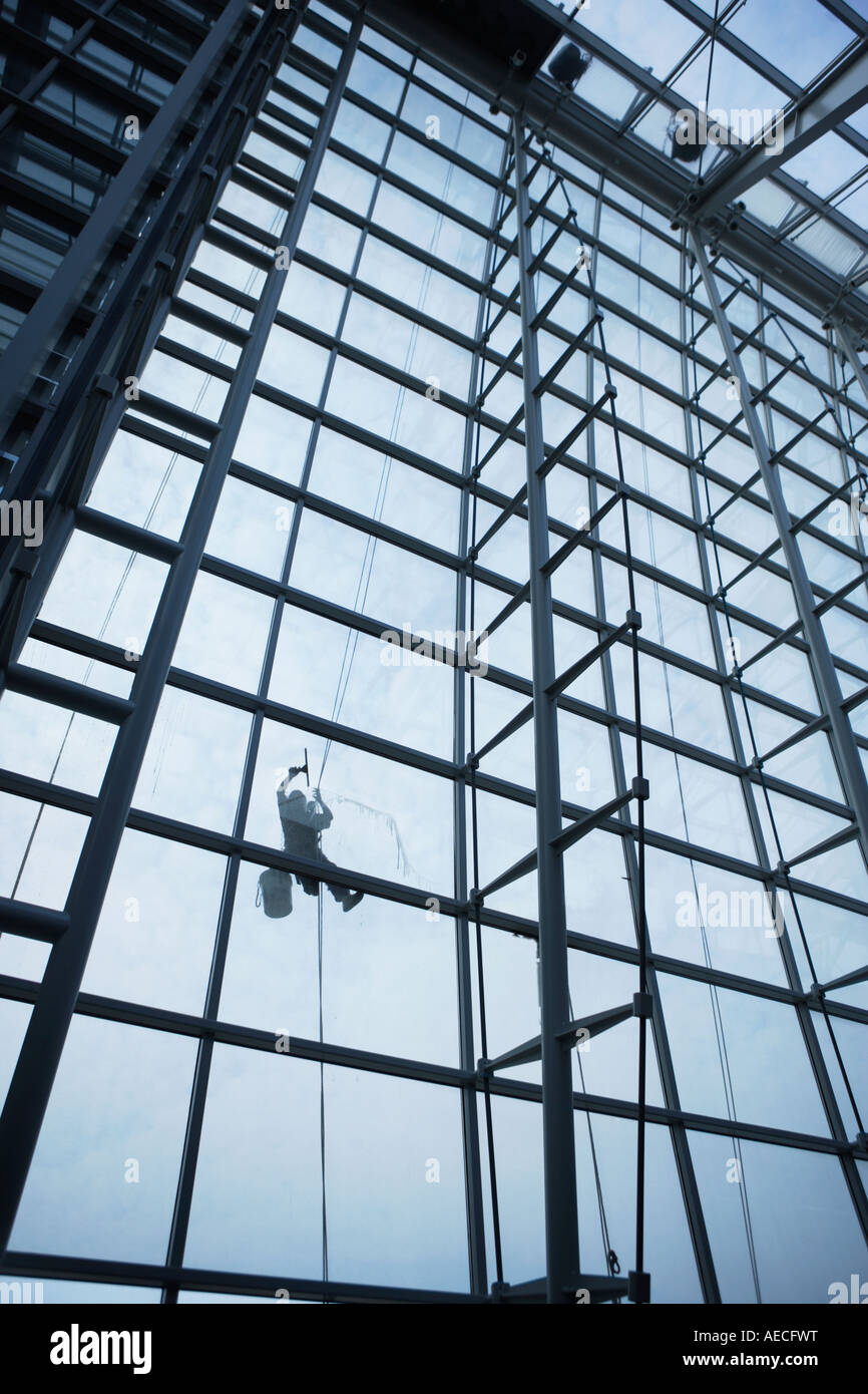 Low angle view of window washer hanging outside building Stock Photo ...