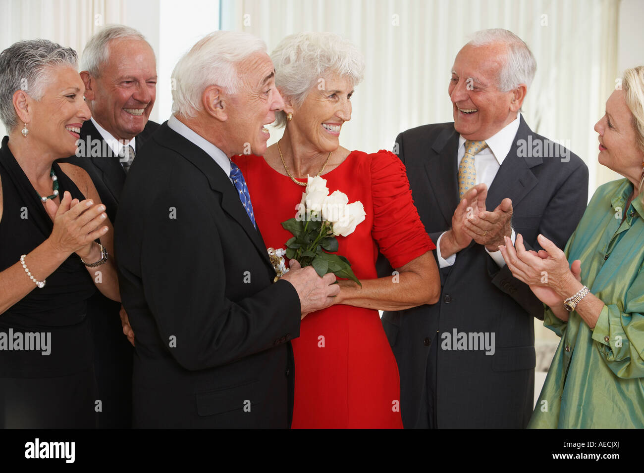 Senior man giving wife bouquet of flowers while friends clap Stock ...