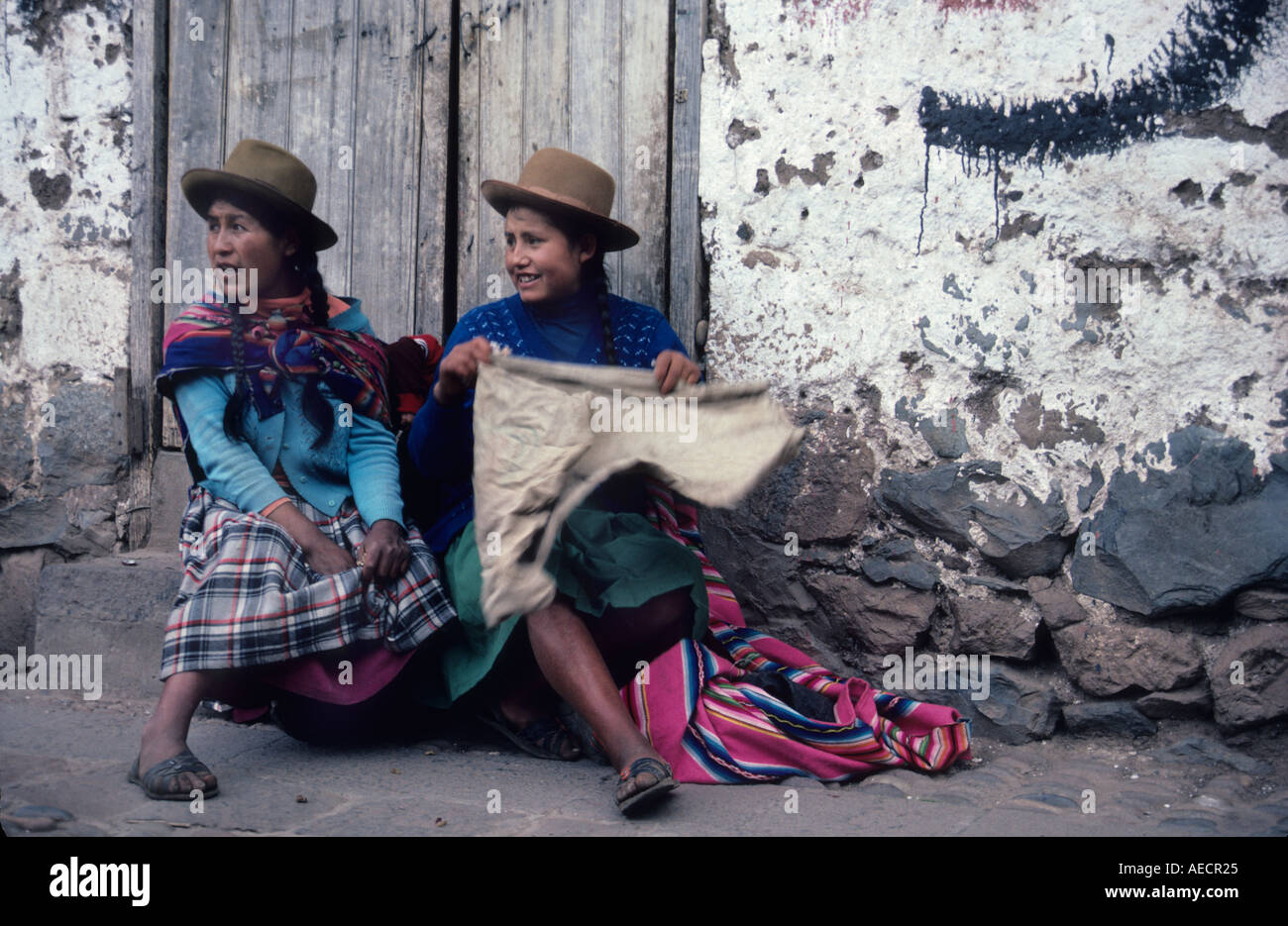 Two Peruvian women talk sitting on doorway entrance Stock Photo - Alamy