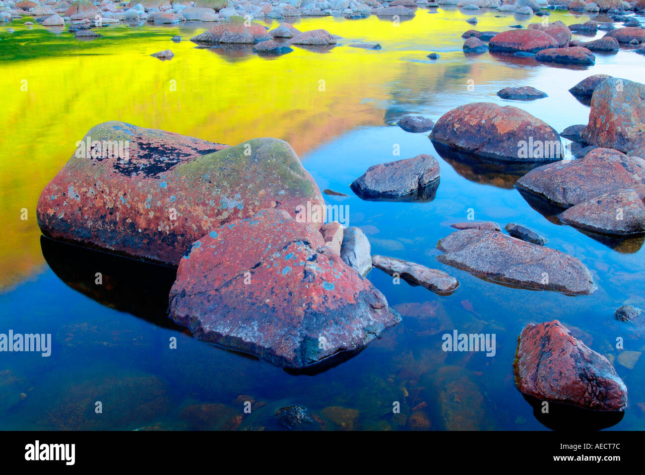 reflections of setting sun against hillside in river, creating golden ...