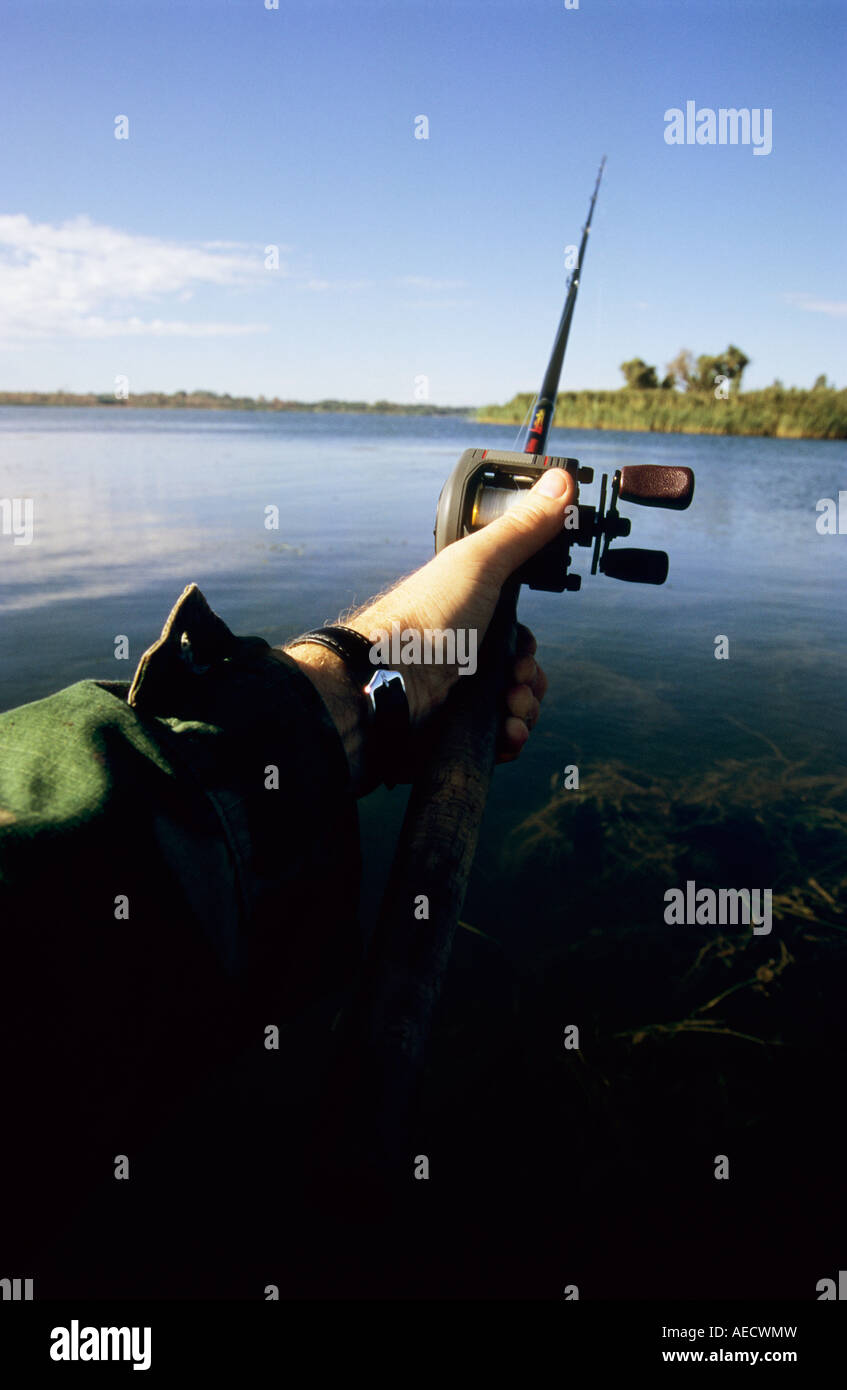 Hand holding fishing rod with bait casting reel waiting for fish to ...