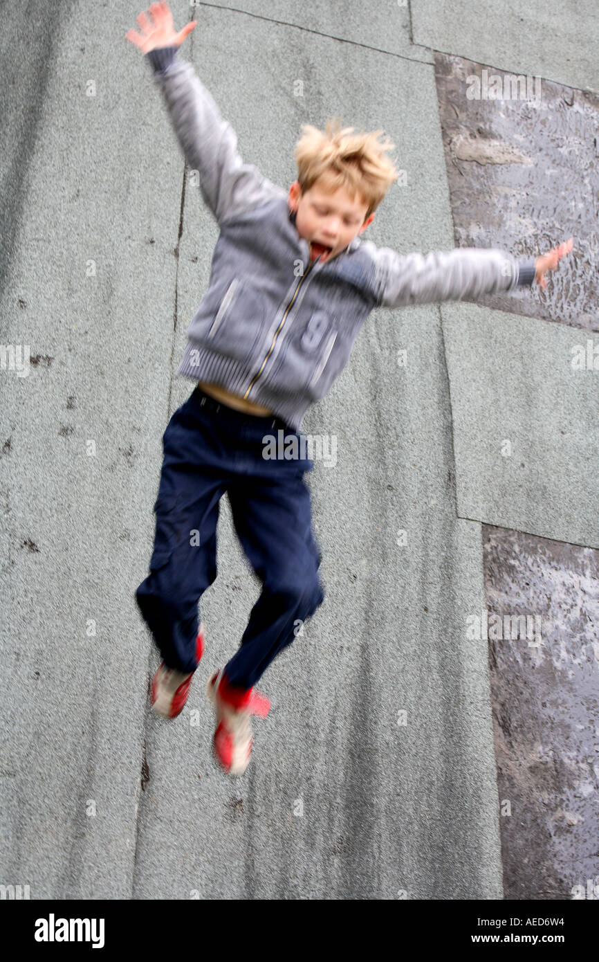 Vertical colour dramatic portrait of young boy jumping down from height ...