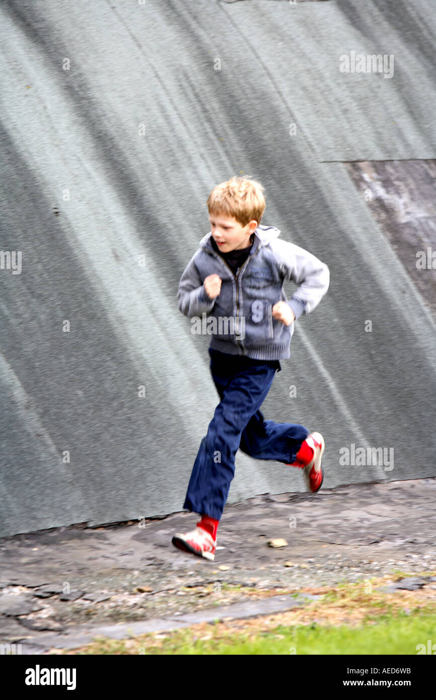 Vertical full length portrait of young boy running at full speed ...