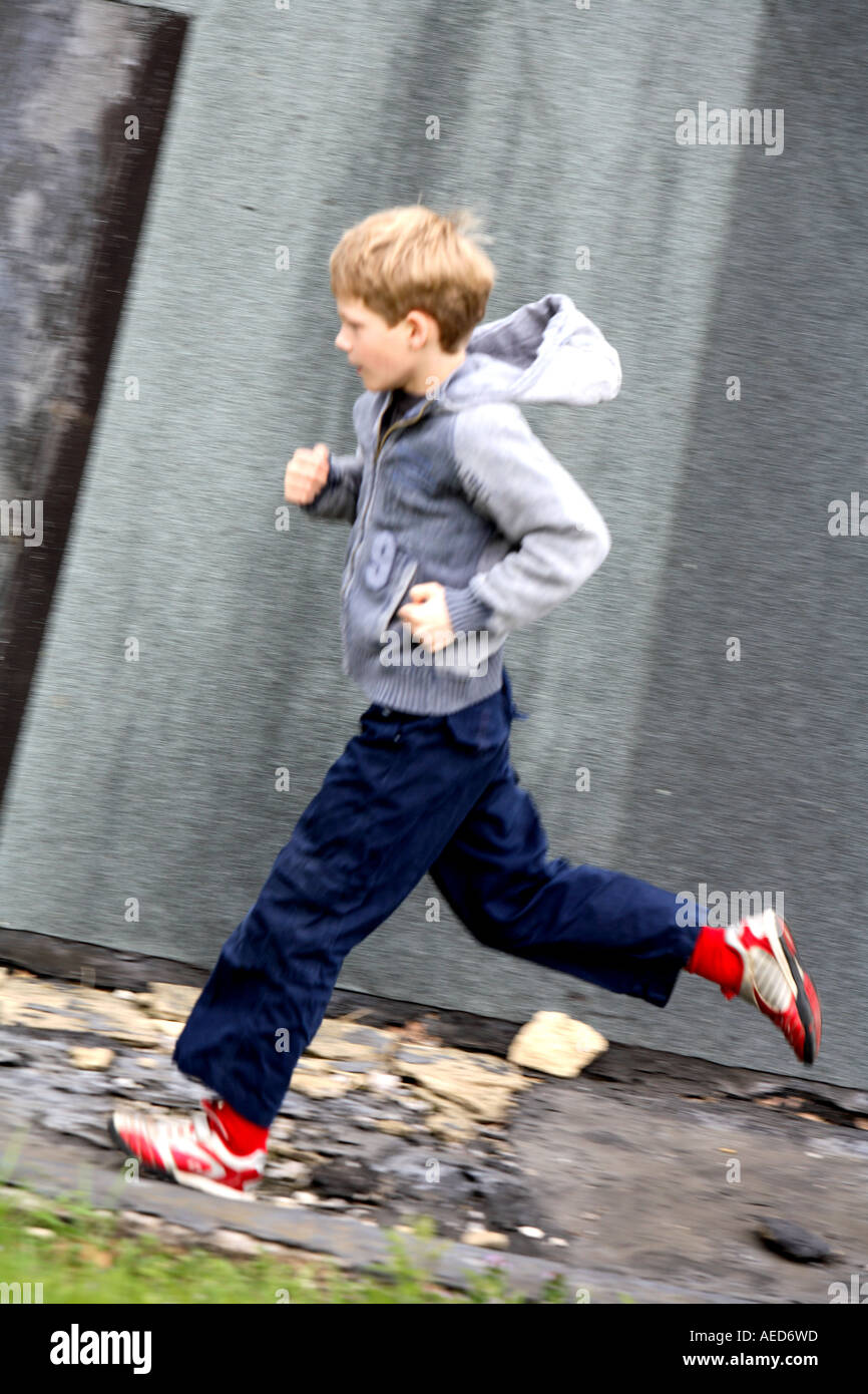Vertical full length portrait of young boy running at full speed ...