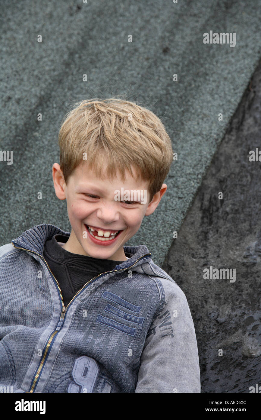 Vertical close up colour portrait of handsome young blond boy laughing ...