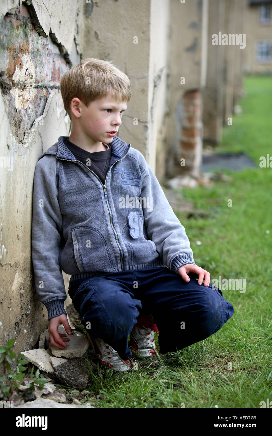 Vertical 3/4 length portrait of young sad looking boy outdoors in ...