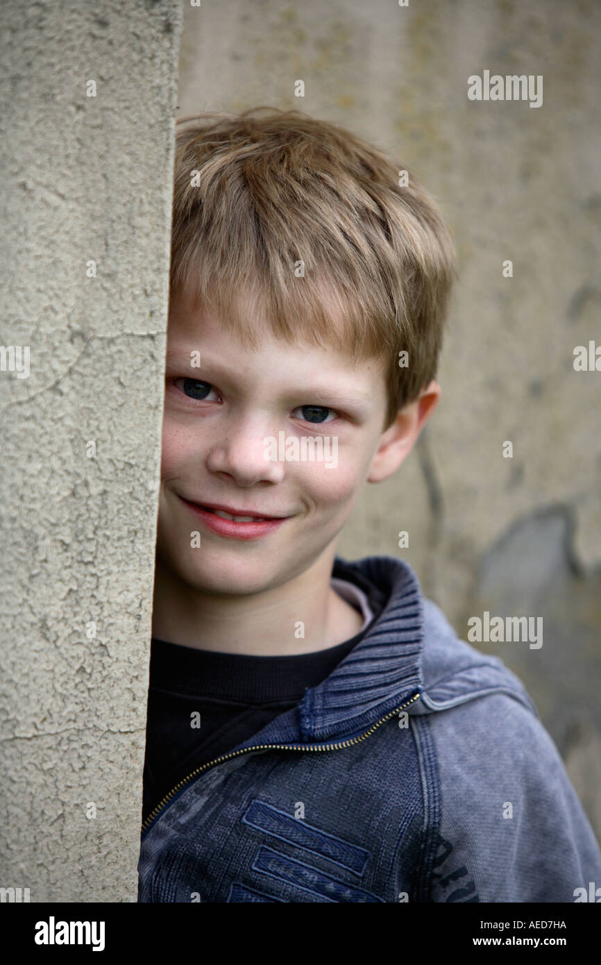 Vertical close up portrait of young cheeky looking boy outdoors in ...