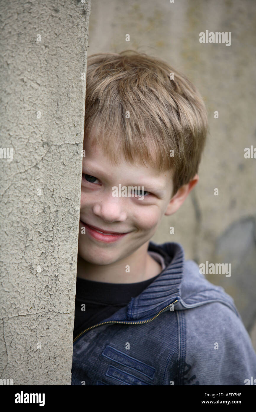 Vertical close up portrait of young cheeky looking boy outdoors in ...