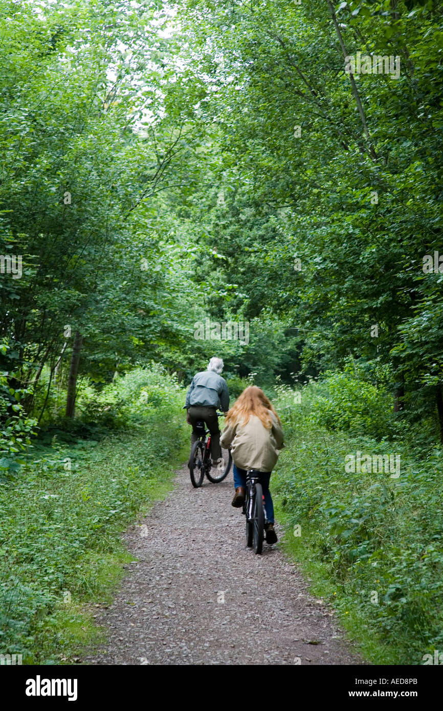 Two adults cycling on a sustrans cycle path made from a disused railway ...