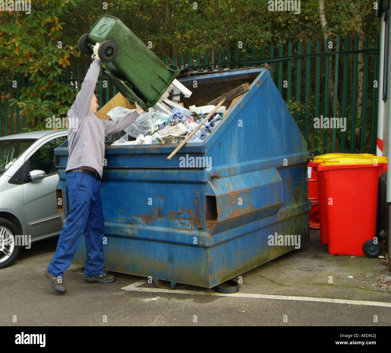 A man is emptying waste into a commercial rubbish container Stock Photo ...