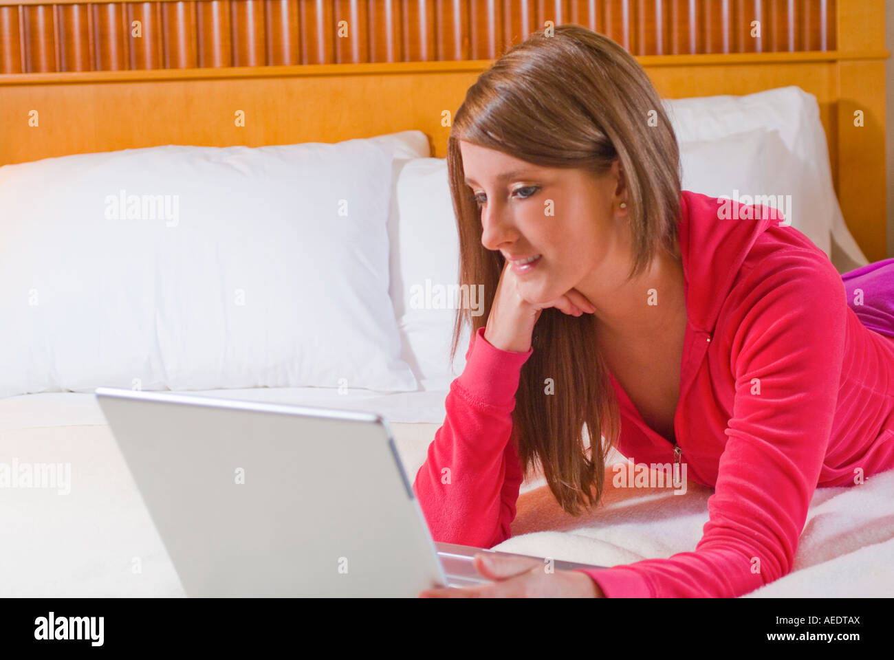 Young girl sitting on bed using laptop computer Stock Photo - Alamy