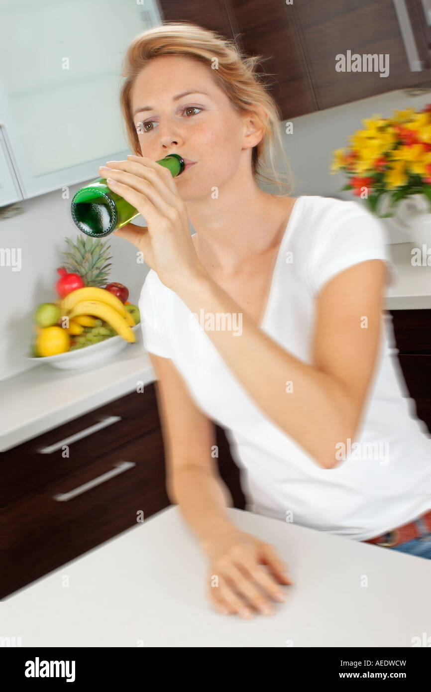 WOMAN IN KITCHEN DRINKING FROM BOTTLE OF BEER Stock Photo - Alamy