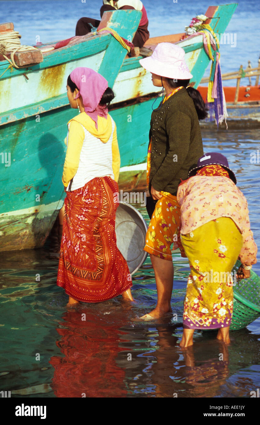 Cham women in colourful sarongs standing by fishing boats on the Sanke ...