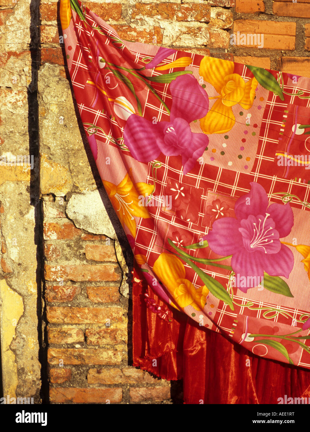 Brightly patterned red fabric hanging on a weathered decaying brick ...