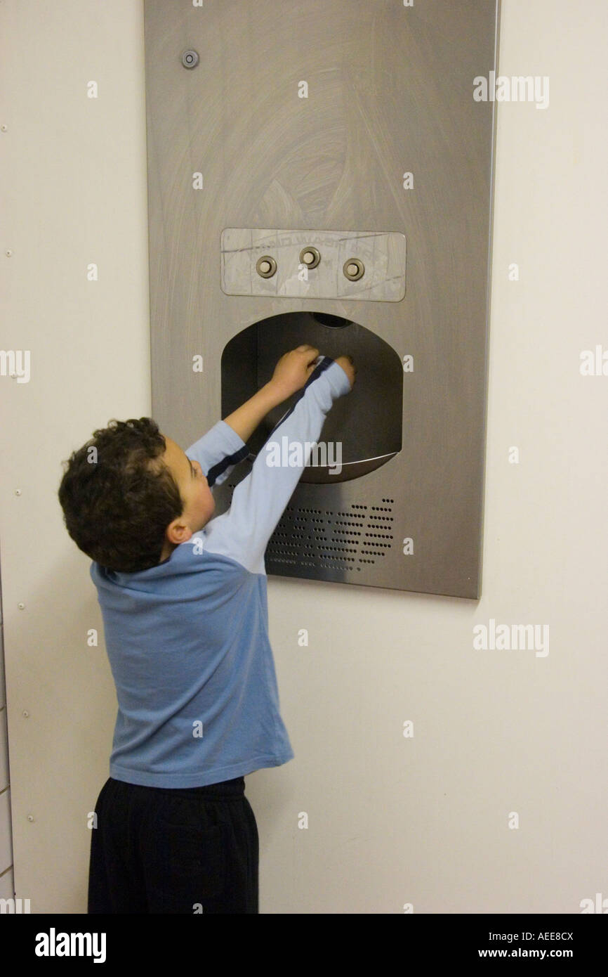 Little boy using an automatic hand washing machine in a public toilet ...