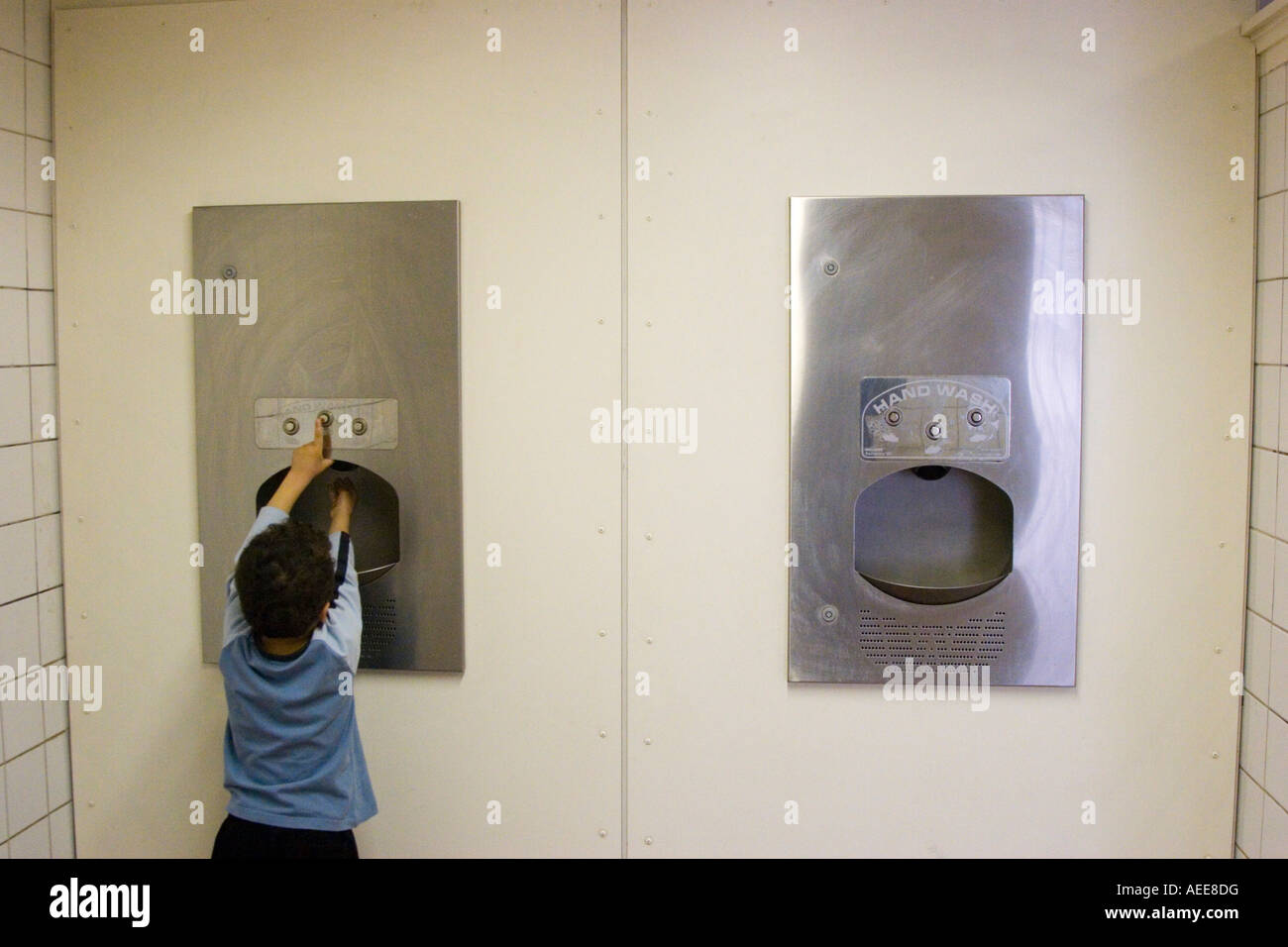 Little boy using an automatic hand washing machine in a public toilet ...