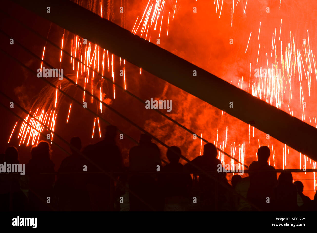 People silhouetted by glowing red sky of firework display during Aste ...