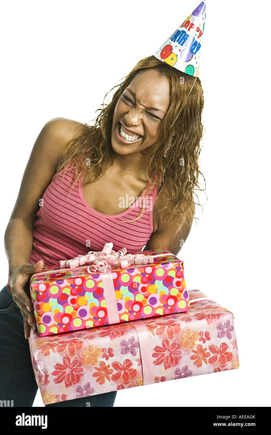 A young woman holding presents and wearing a party hat in a studio ...