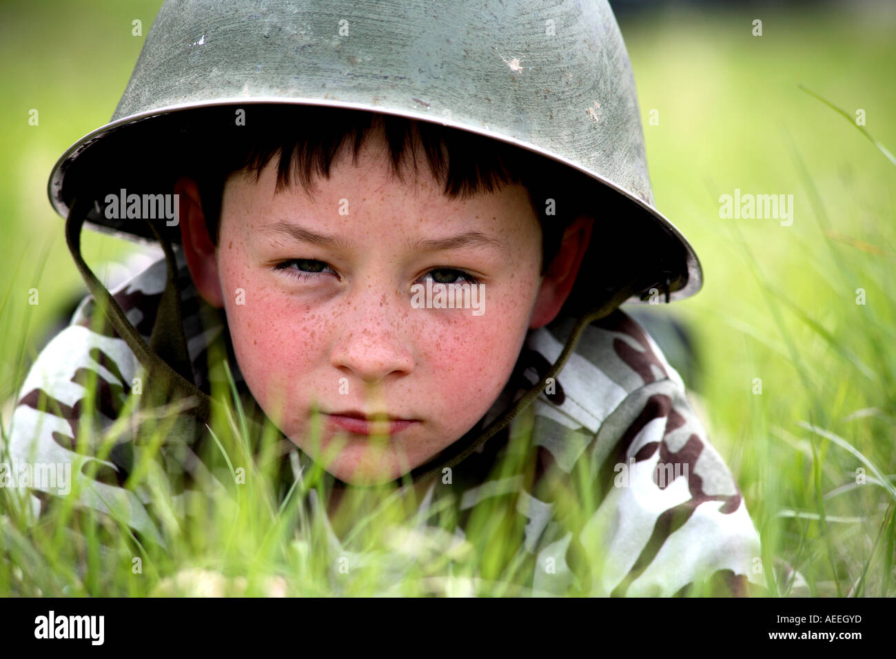 Vertical close up portrait of young boy in role play as soldier lying ...