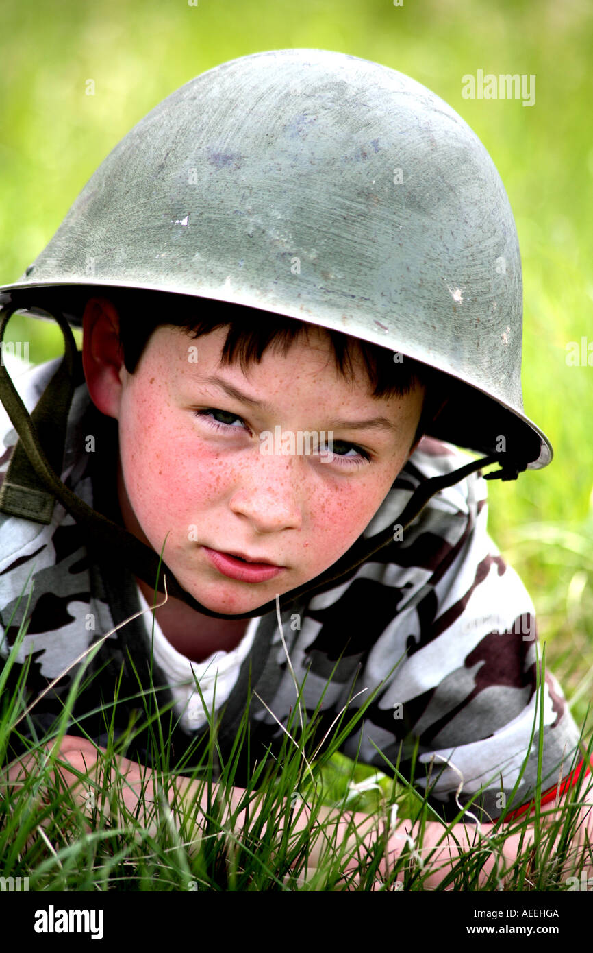 Vertical close up portrait of young boy in role play as soldier lying ...