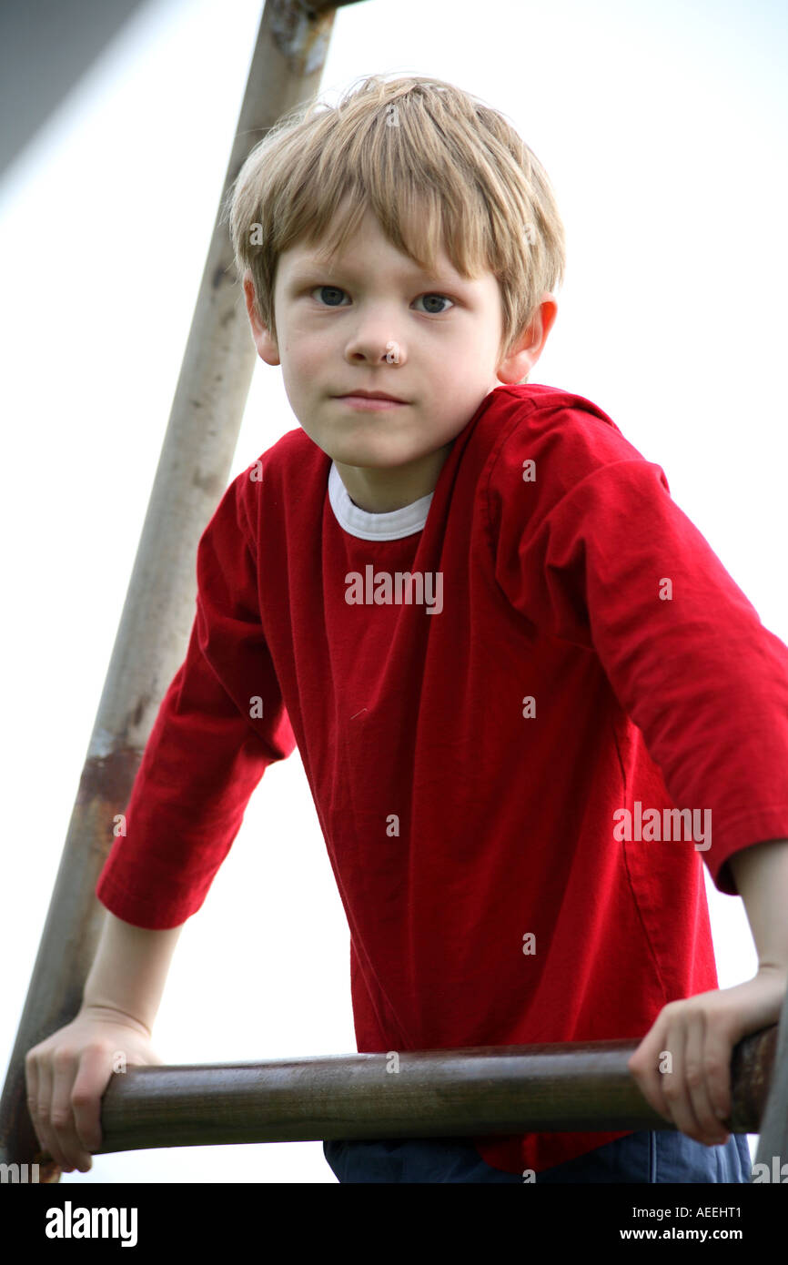 Vertical colour portrait of young boy climbing on metal ladder on ...